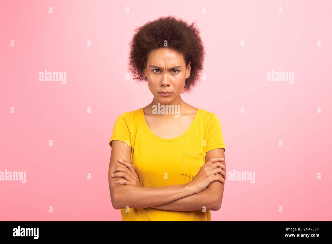 Sad strict angry young black curly female crossed her arms on chest and ...