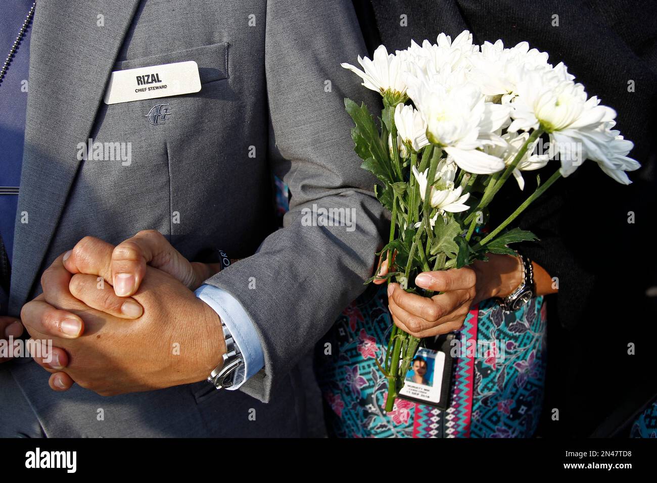 A Malaysia Airlines crew member holds flowers as she waits outside ...