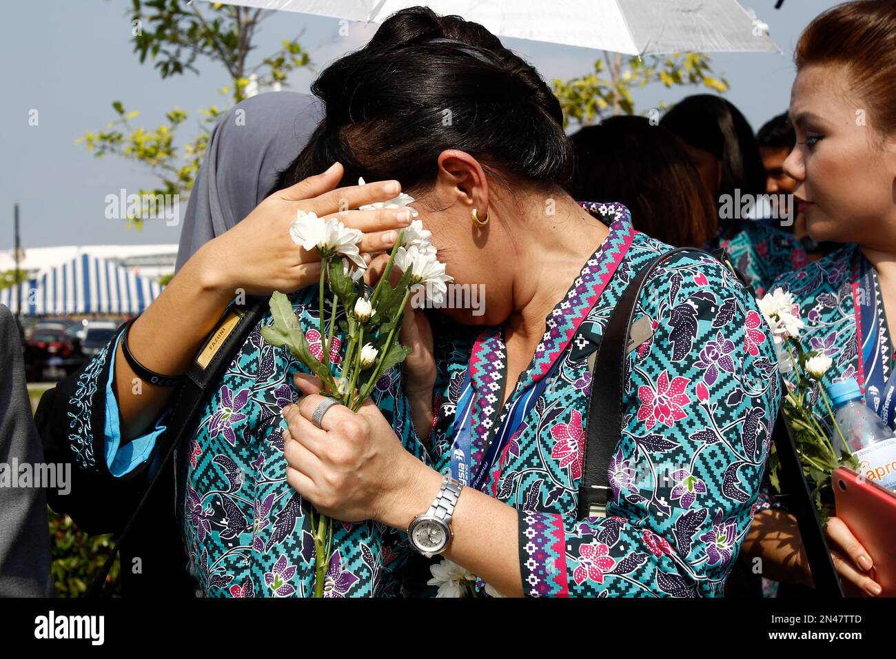 Malaysia Airlines crew members embrace each other as they wait outside ...