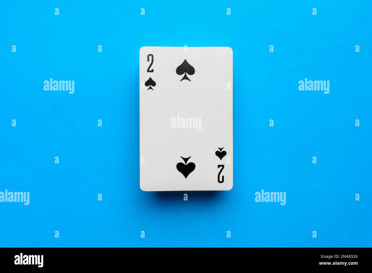 Playing card deuce of spades on a blue background Stock Photo - Alamy