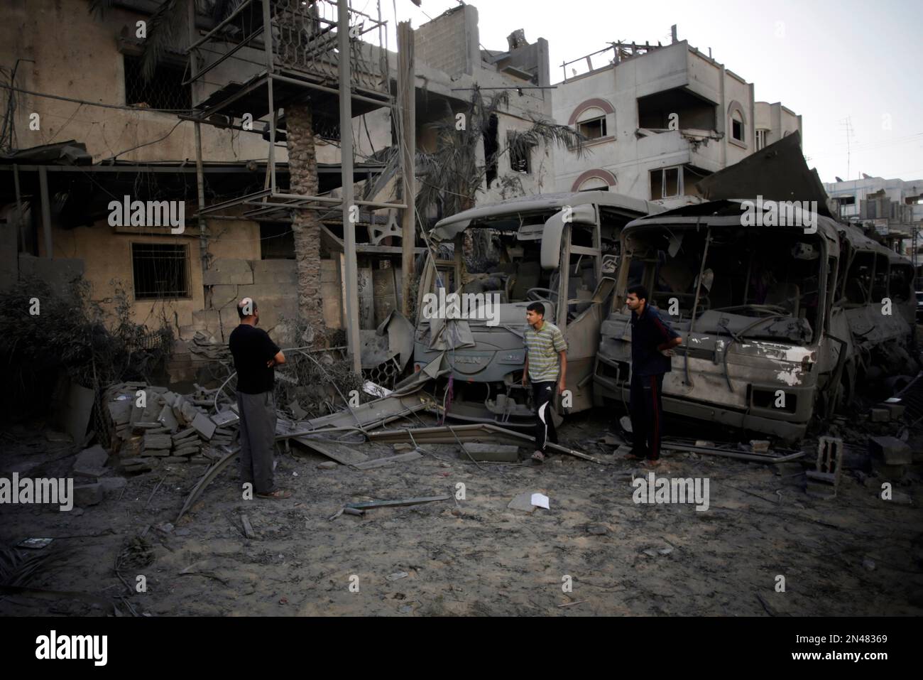 Palestinians check the damage of their destroyed houses and buses ...