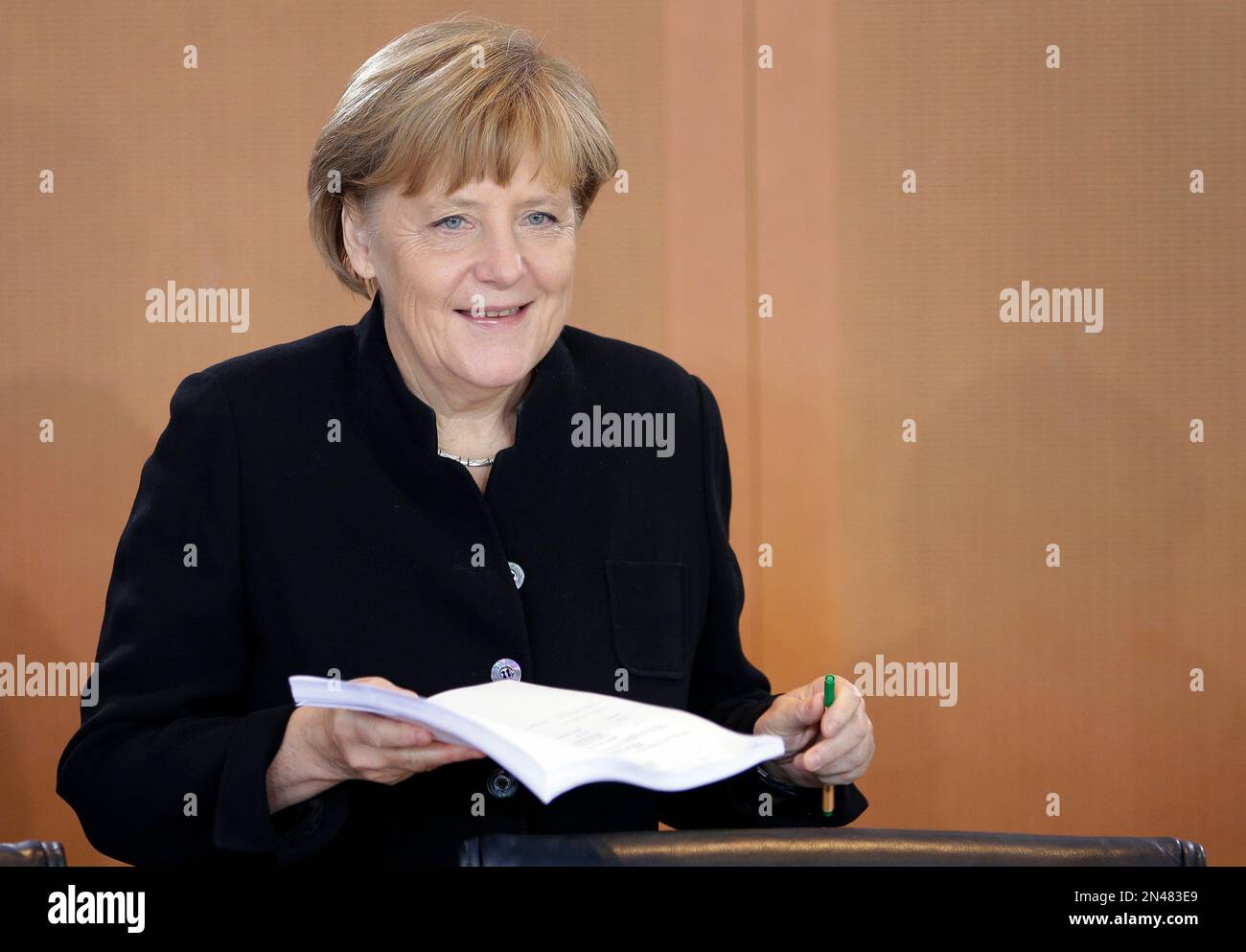 German Chancellor Angela Merkel holds files as she arrives for the ...
