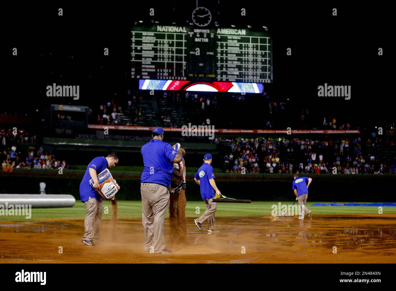 The grounds crew works on the field after a heavy rain soaked Wrigley ...