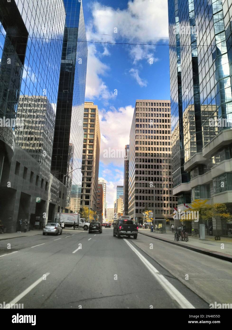 A vertical of high modern buildings from a road with cars in Ottawa ...