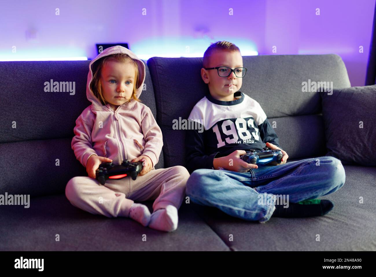 The boy Danya and his younger sister Emilia play on the console Stock ...