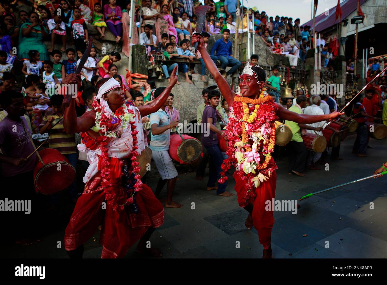 Hindu priests, faces smeared with color and sacrificial blood, perform ...