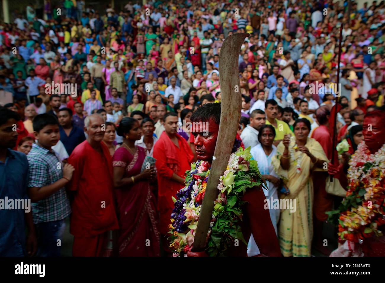 A Hindu priest, face smeared with color and sacrificial blood, performs ...