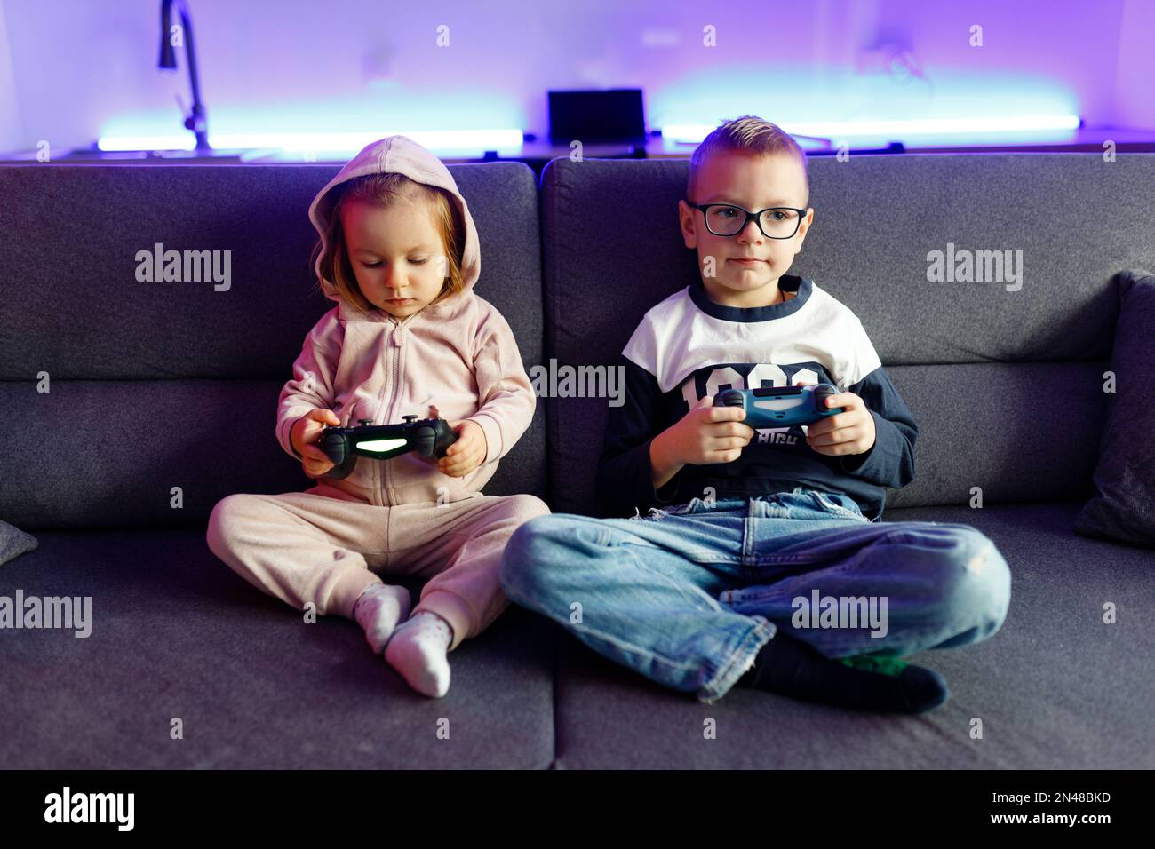 The boy Danya and his younger sister Emilia play on the console Stock ...