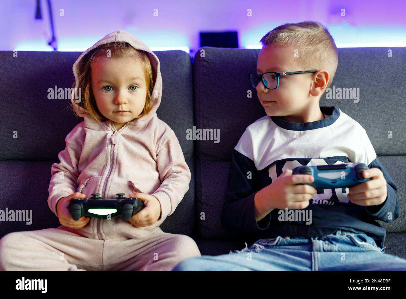 The boy Danya and his younger sister Emilia play on the console Stock ...