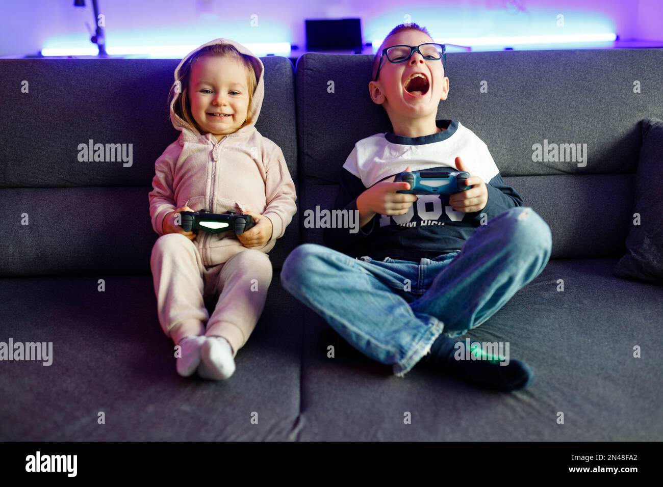 The boy Danya and his younger sister Emilia play on the console Stock ...