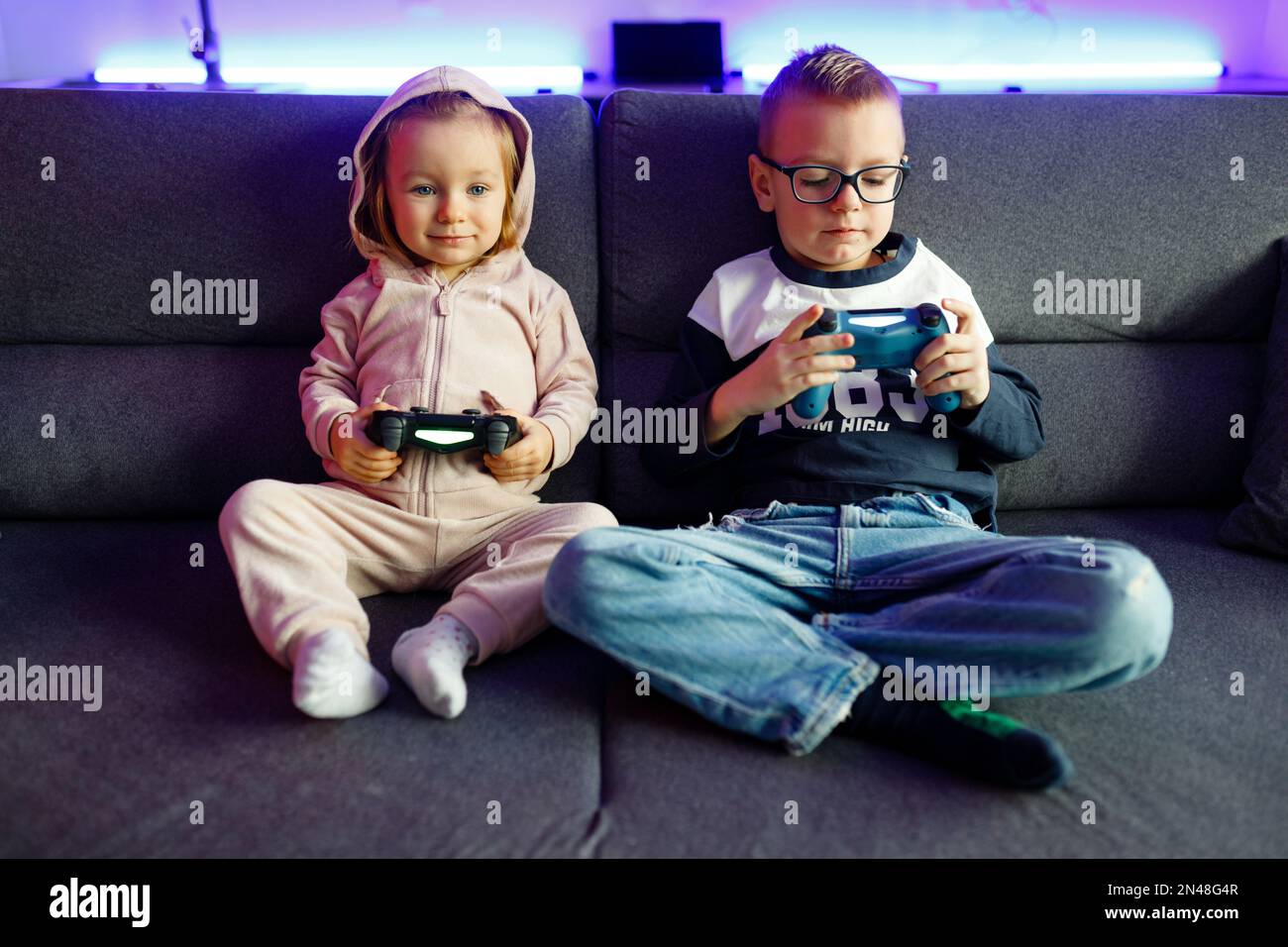 The boy Danya and his younger sister Emilia play on the console Stock ...