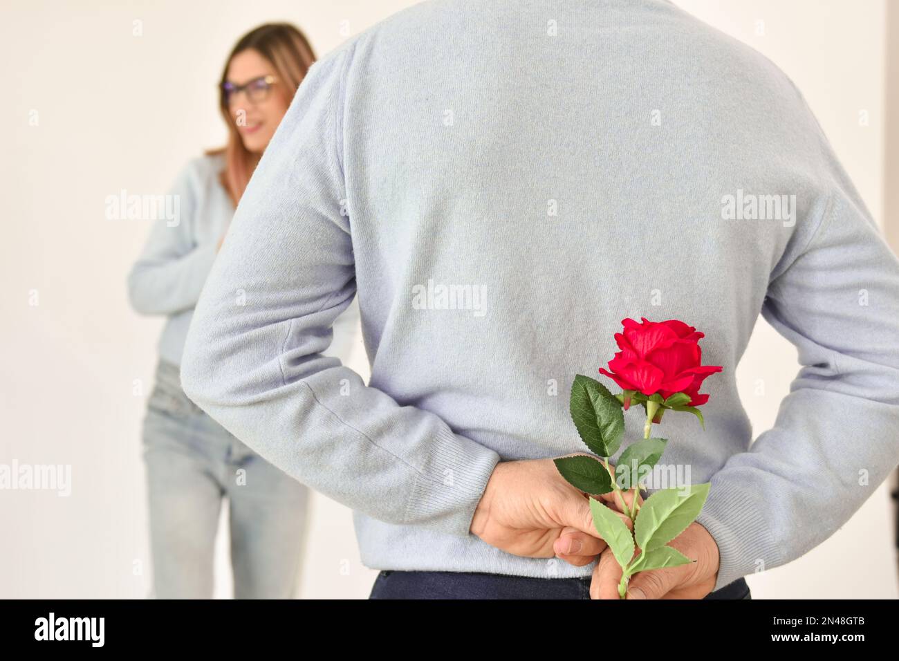 A man holding a red rose behind his back Stock Photo - Alamy