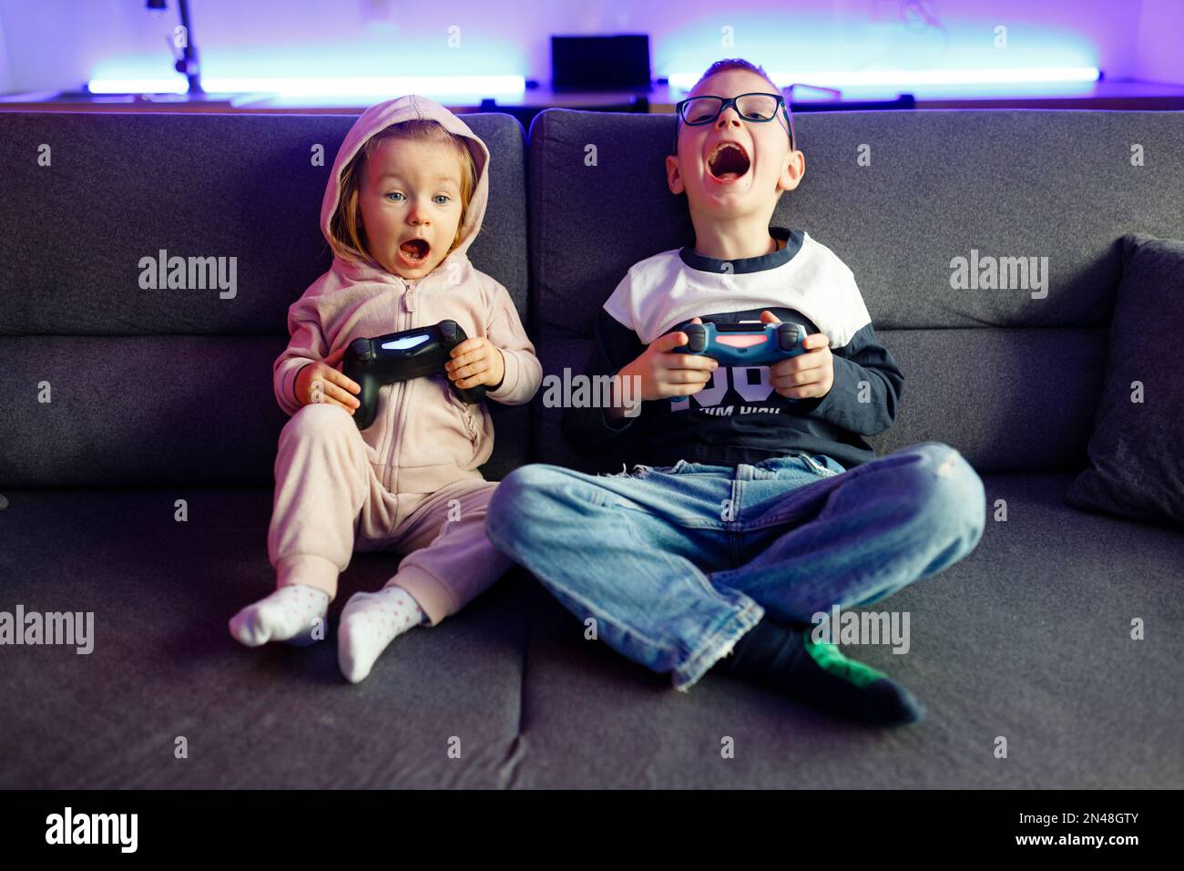 The boy Danya and his younger sister Emilia play on the console Stock ...