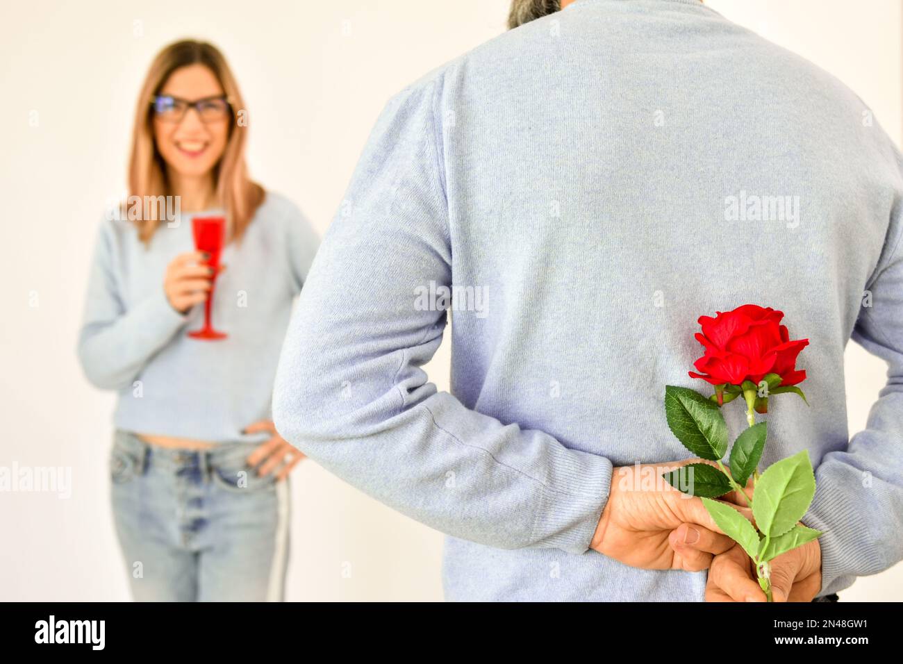 A man holding a red rose behind his back Stock Photo - Alamy