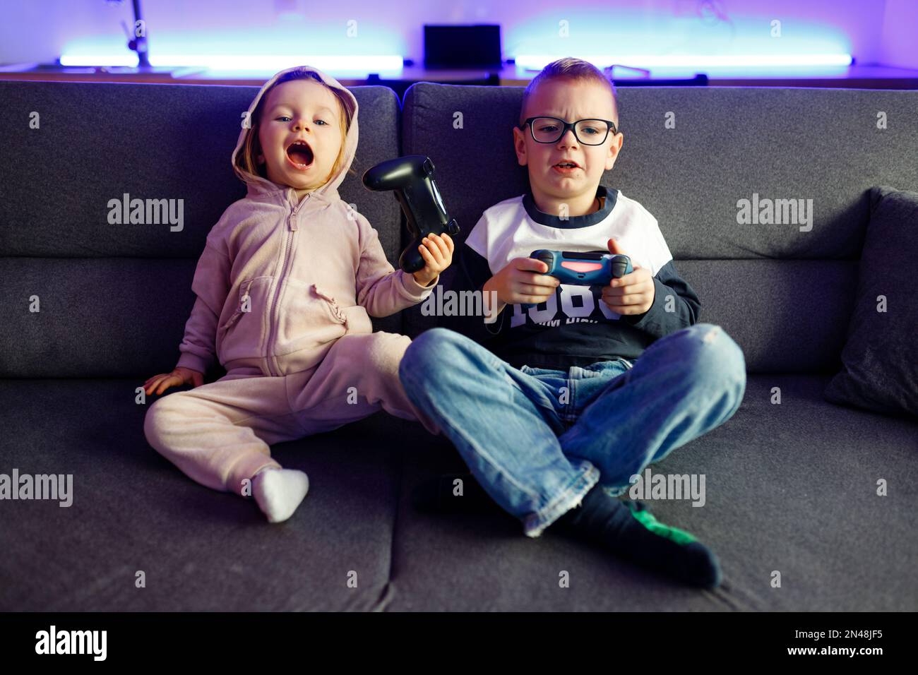 The boy Danya and his younger sister Emilia play on the console Stock ...