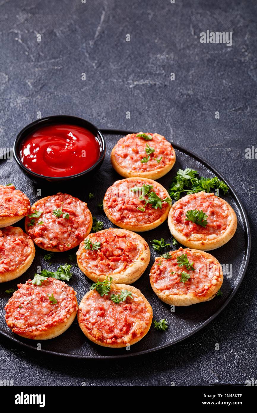 mini pizzas, piccolinis, with ham and pecorino cheese on black plate ...