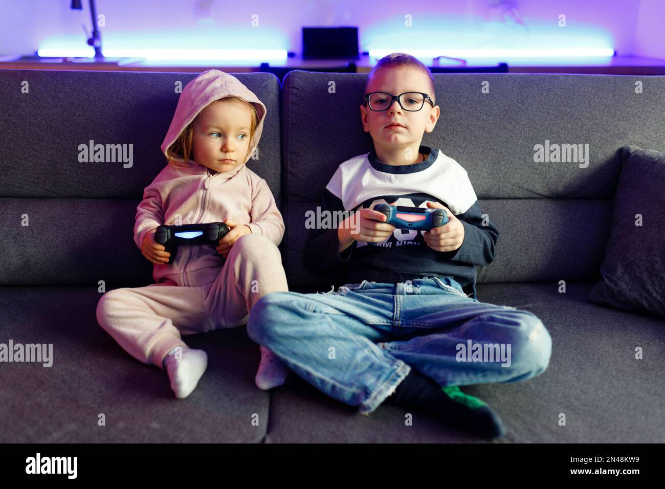 The boy Danya and his younger sister Emilia play on the console Stock ...