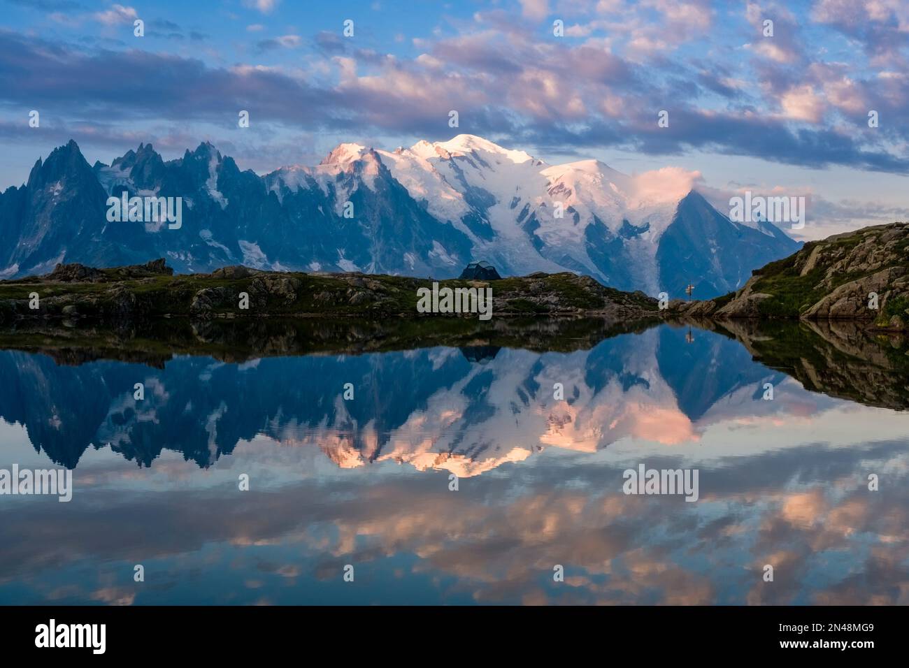 The peaks of the Mont Blanc massif and some clouds, reflecting on the surface of Lacs des ...