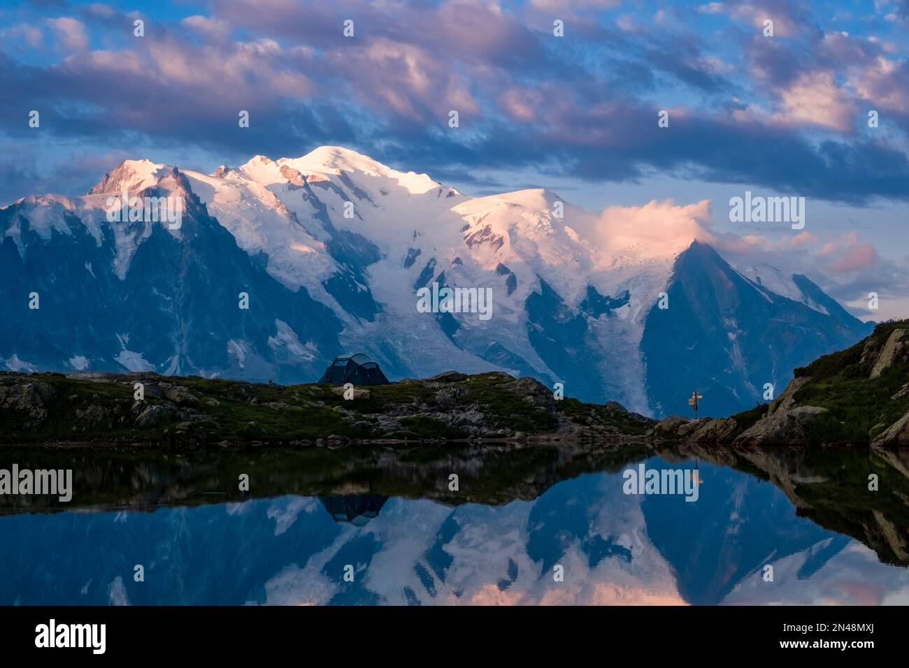 The peaks of the Mont Blanc massif and some clouds, reflecting on the surface of Lacs des ...
