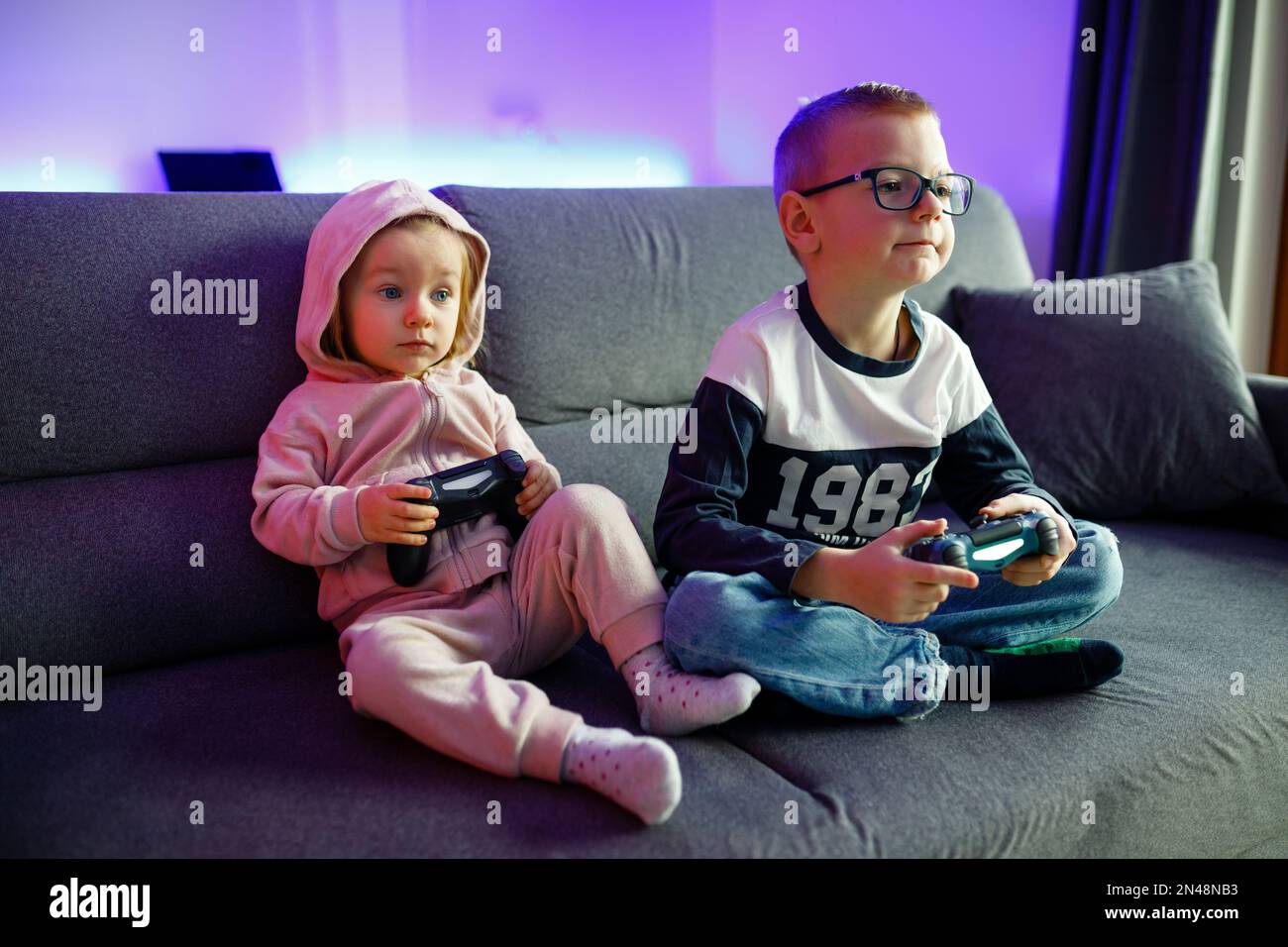 The boy Danya and his younger sister Emilia play on the console Stock ...