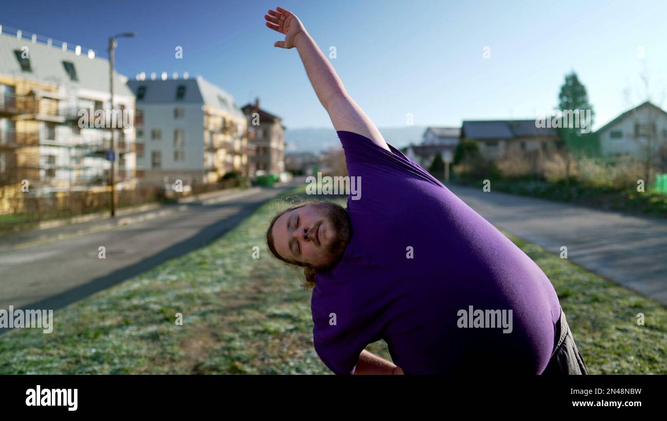 An overweight person stretching body outdoors. A male caucasian person ...