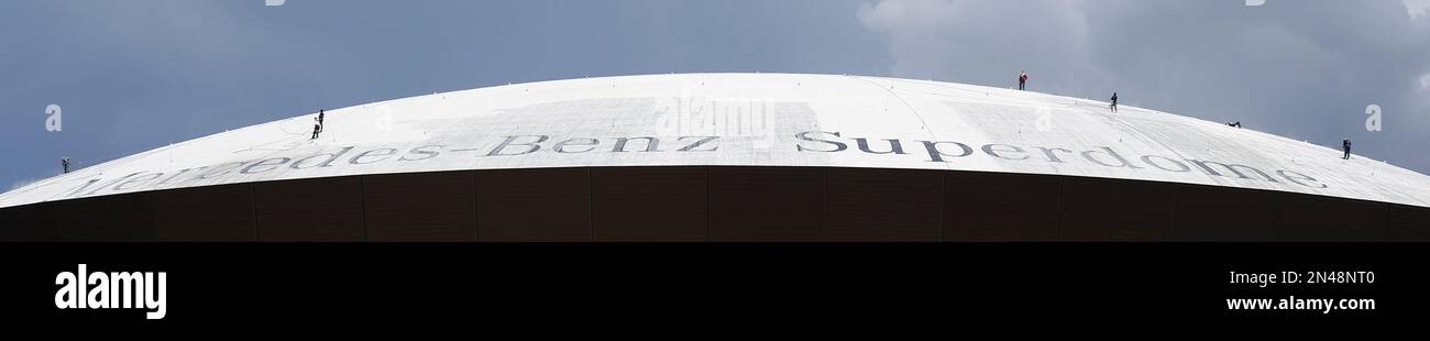 Workmen use safety lines to "walk" across the top of the Mercedes Benz ...