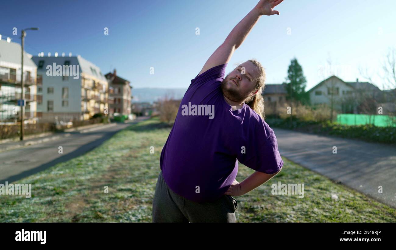 An overweight person stretching body outdoors. A male caucasian person ...