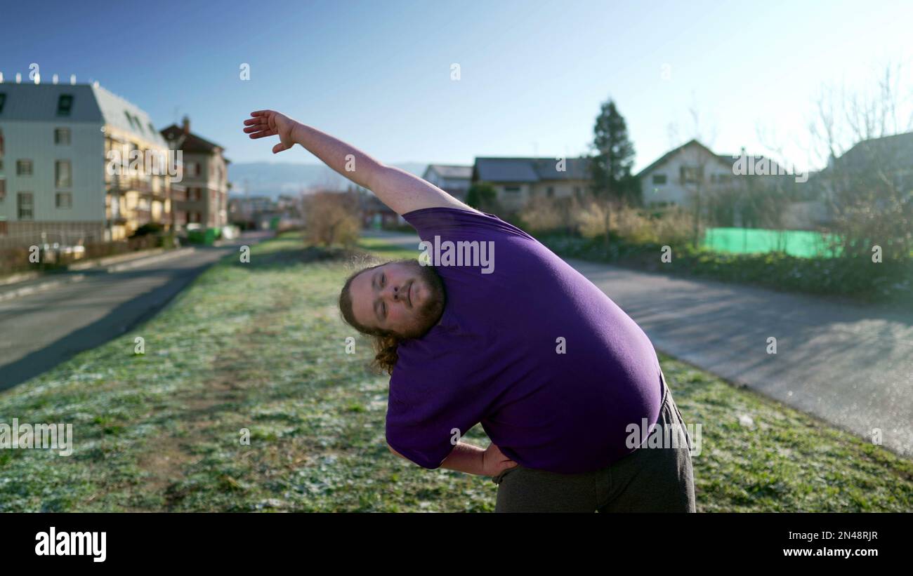 An overweight person stretching body outdoors. A male caucasian person ...