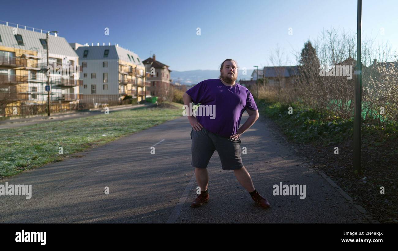 One overweight man stretching outside in street preparing for a run ...