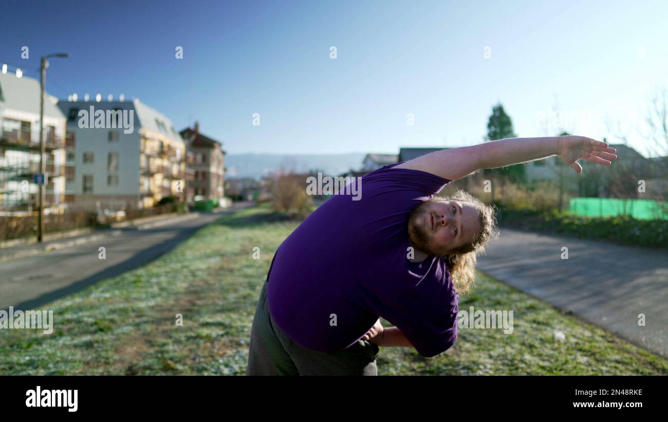 An overweight person stretching body outdoors. A male caucasian person ...