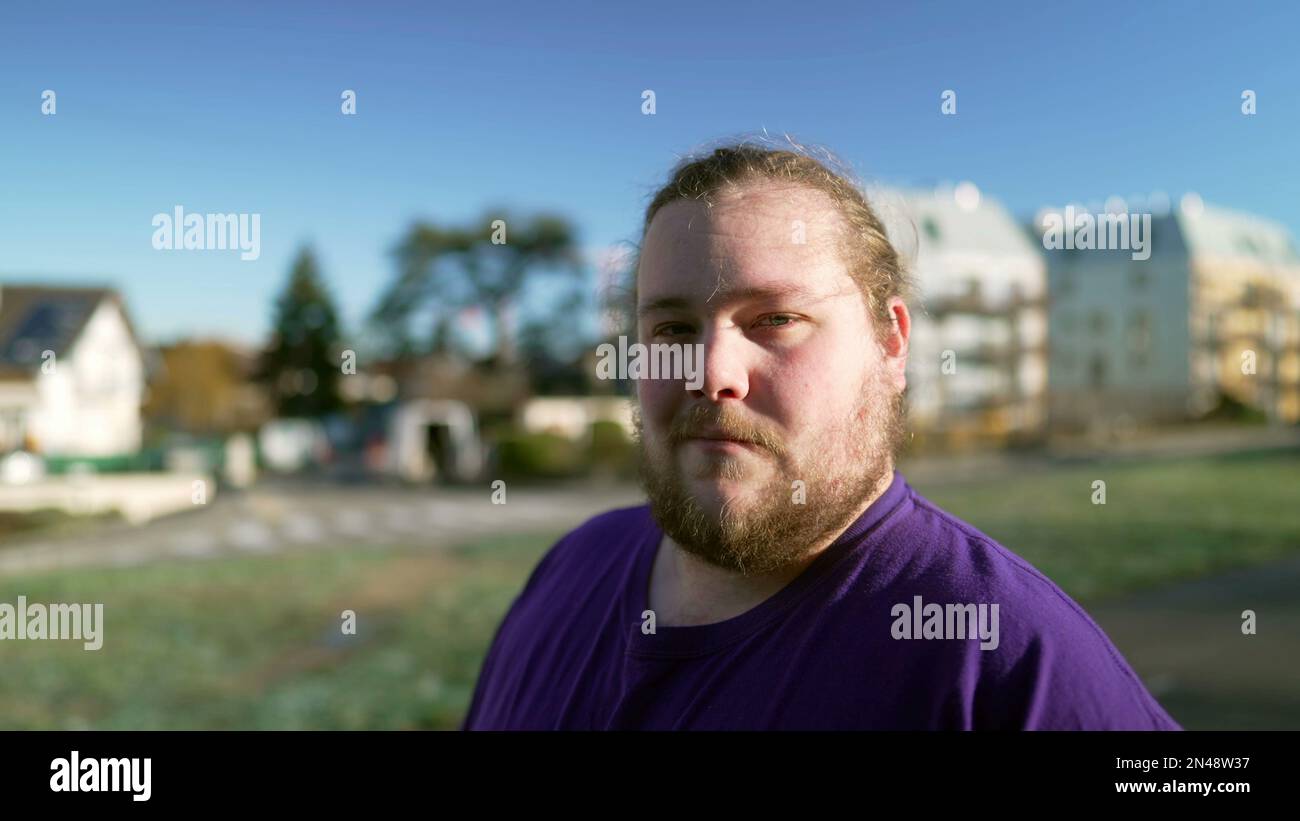 Portrait of a happy overweight young man standing outside looking at ...