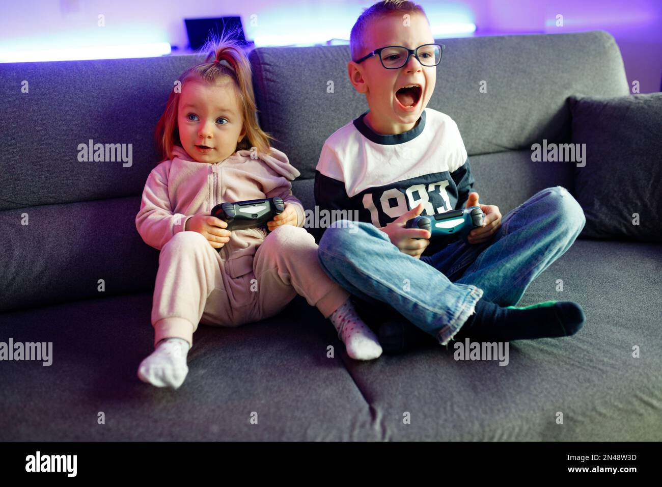 The boy Danya and his younger sister Emilia play on the console Stock ...