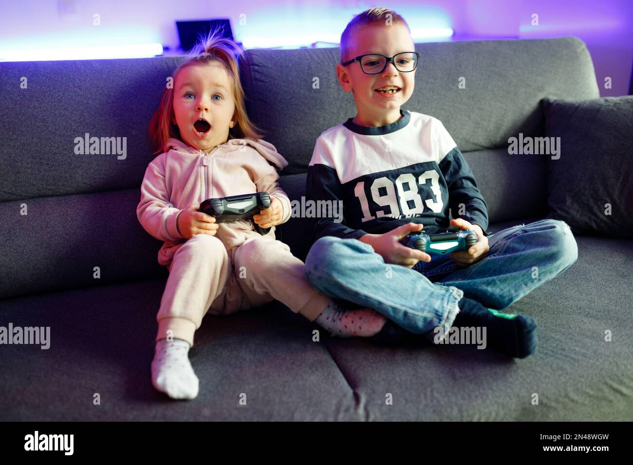 The boy Danya and his younger sister Emilia play on the console Stock ...