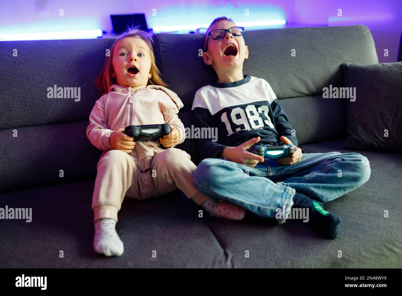 The boy Danya and his younger sister Emilia play on the console Stock ...