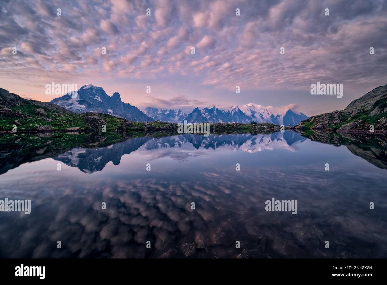 The peaks of the Mont Blanc massif and some clouds are reflecting in the Lacs des Chéserys at ...