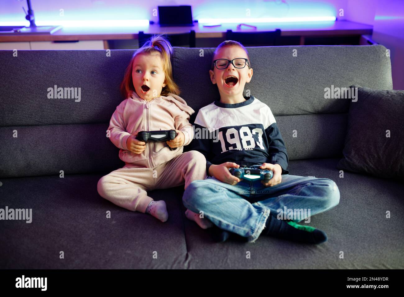 The boy Danya and his younger sister Emilia play on the console Stock ...