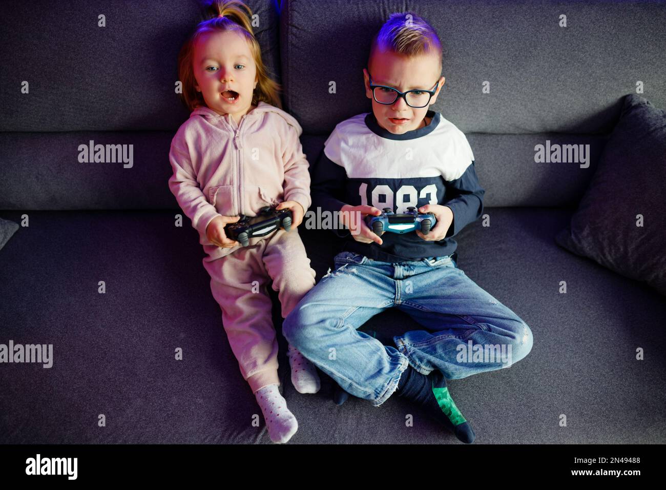 The boy Danya and his younger sister Emilia play on the console Stock ...