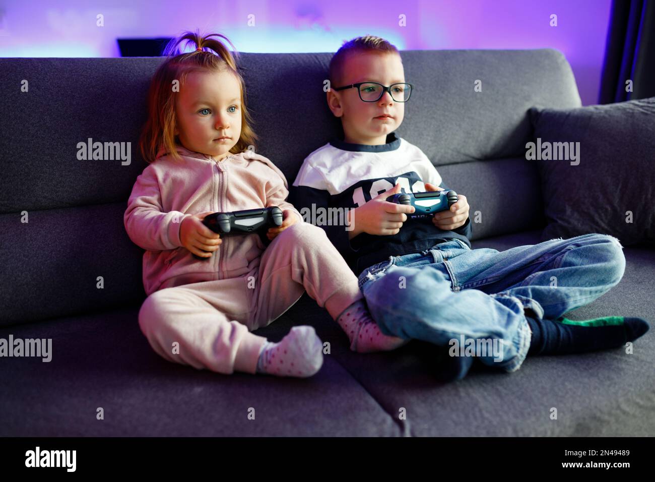 The boy Danya and his younger sister Emilia play on the console Stock ...