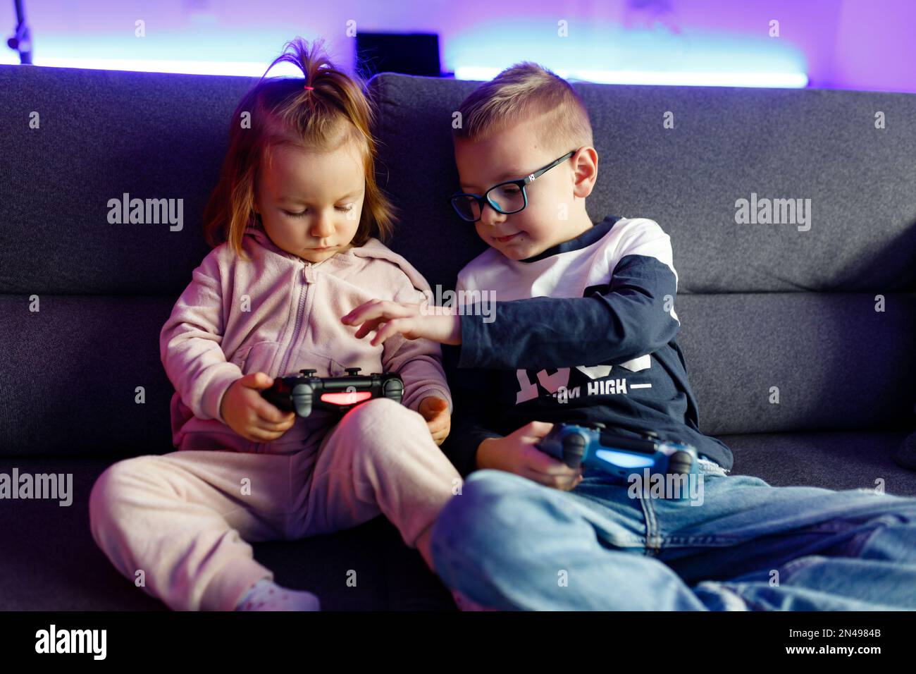 The boy Danya and his younger sister Emilia play on the console Stock ...