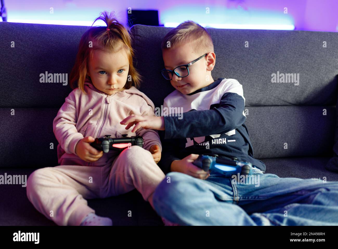 The boy Danya and his younger sister Emilia play on the console Stock ...