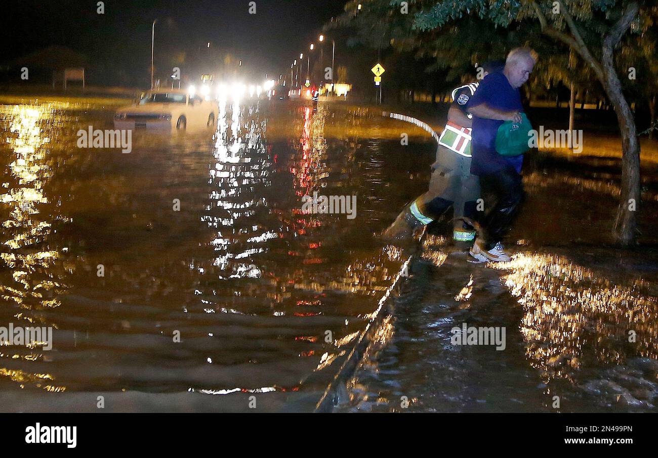 A man is rescued from his car by a Phoenix firefighter as heavy rains ...