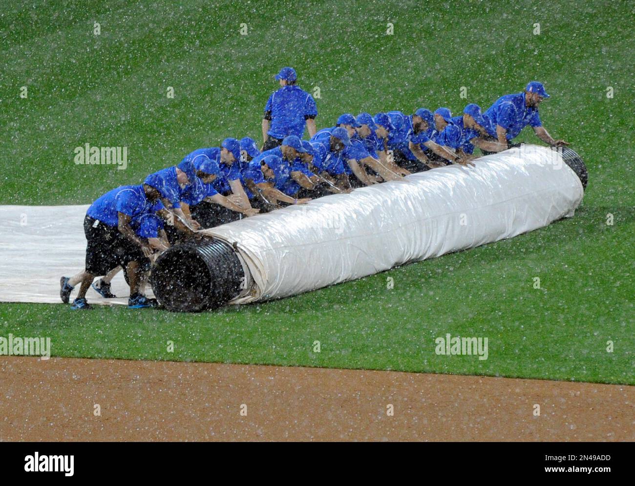 The grounds crew rolls out the tarp to cover the field during a rain ...