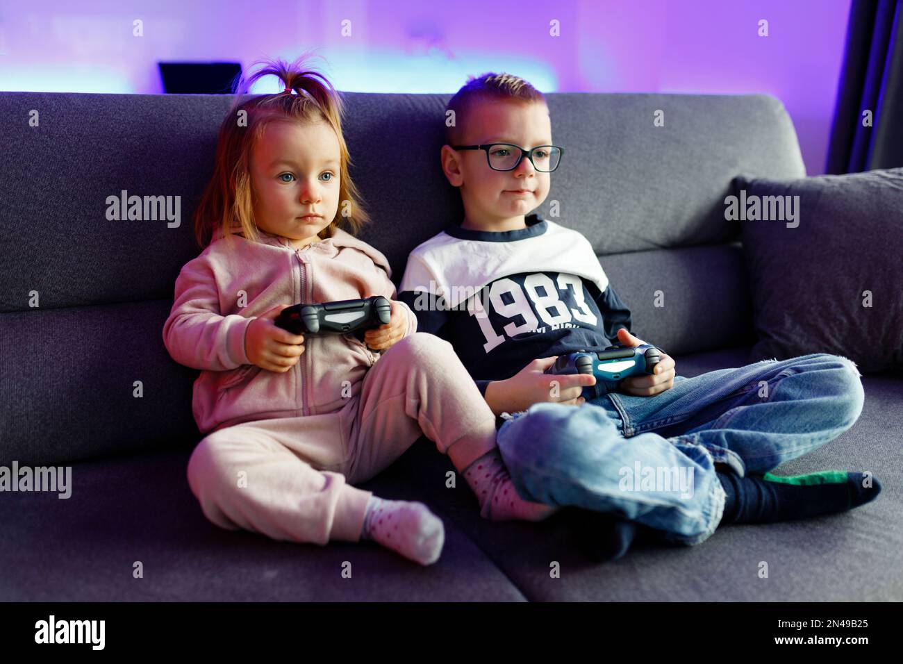 The boy Danya and his younger sister Emilia play on the console Stock ...