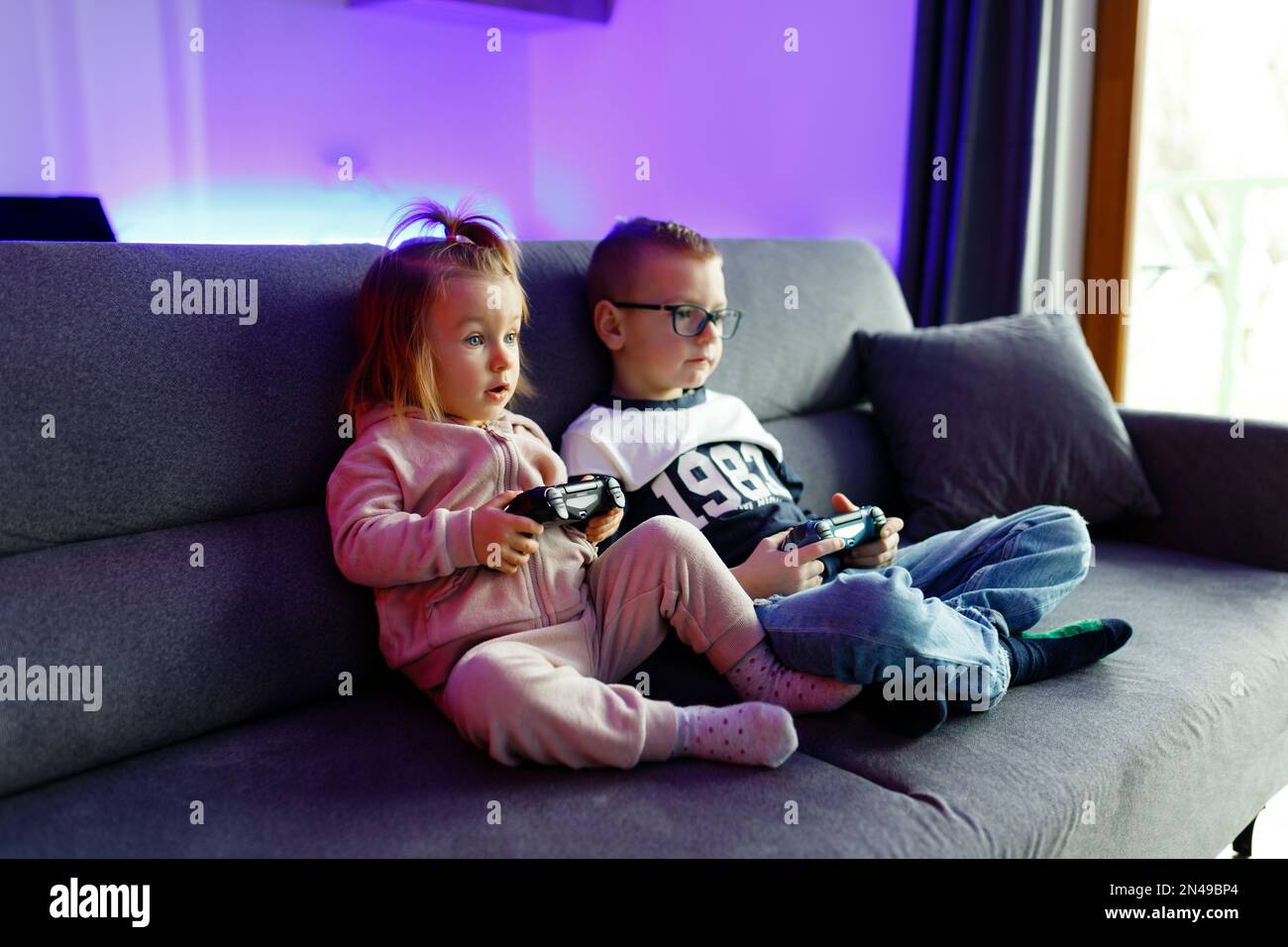 The boy Danya and his younger sister Emilia play on the console Stock ...