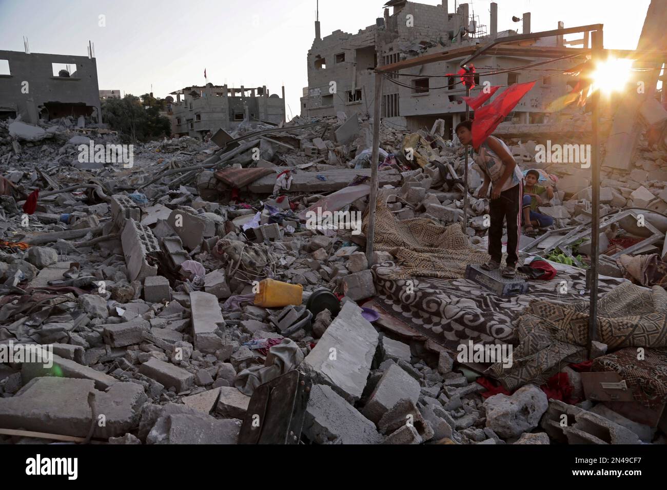 Ahmad and Mahmoud al Masri, sit during the sunset on the rubble of ...
