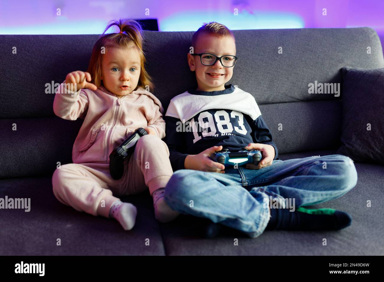 The boy Danya and his younger sister Emilia play on the console Stock ...