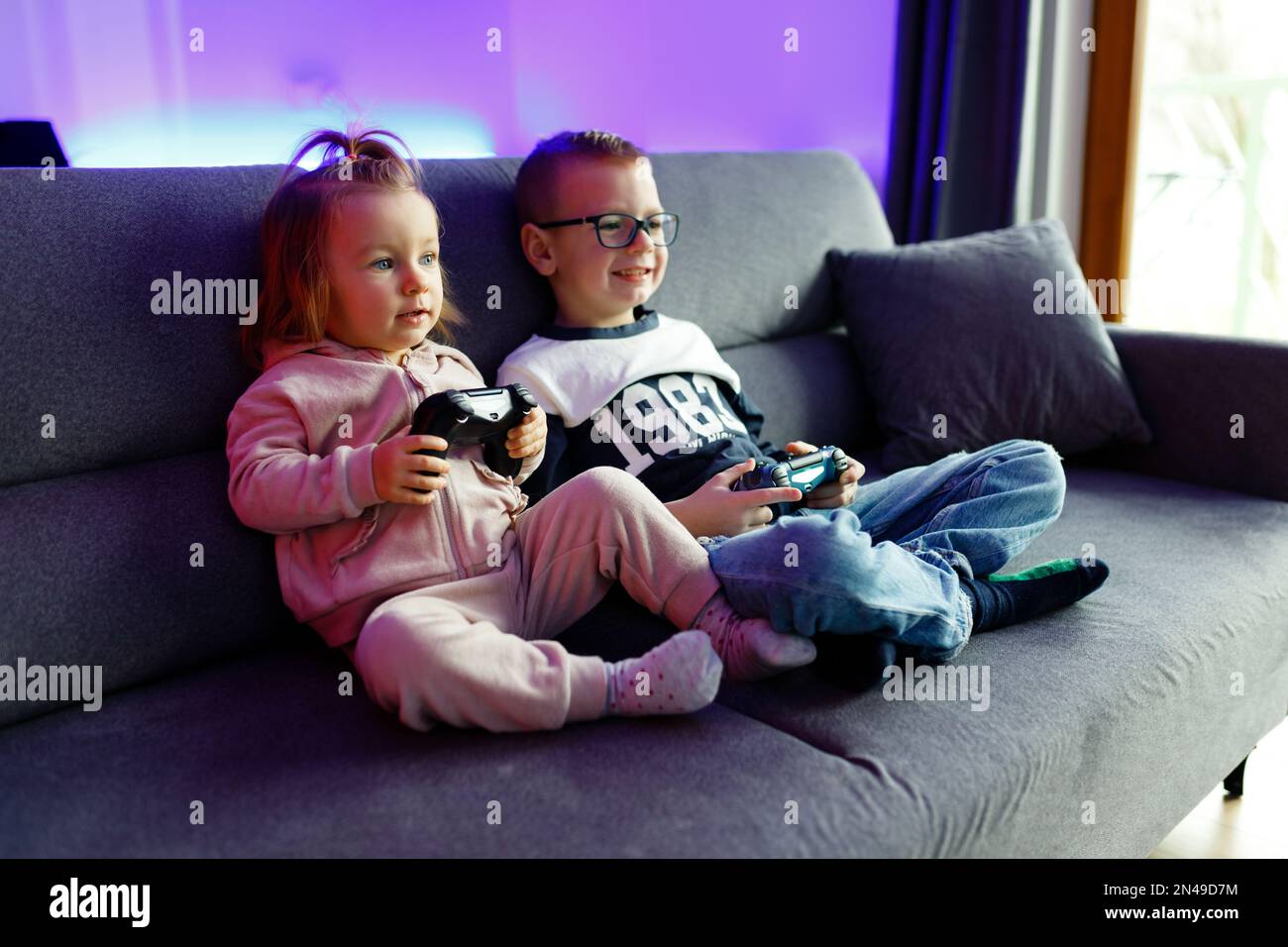 The boy Danya and his younger sister Emilia play on the console Stock ...