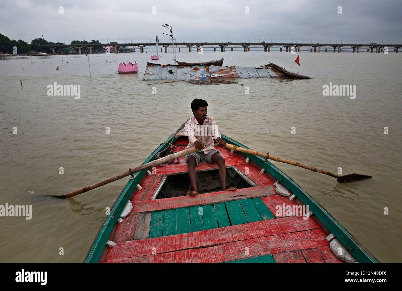 An Indian boatman rows his boat in the River Ganges, flooded after ...