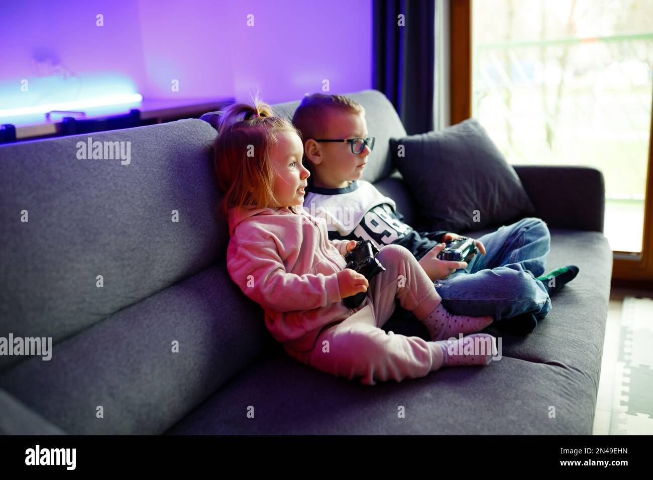 The boy Danya and his younger sister Emilia play on the console Stock ...