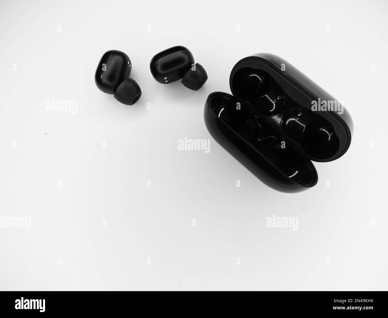 A top view grayscale of wireless earbuds with a black open powerbank on ...